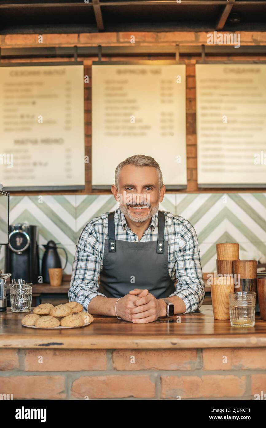 Man standing behind bar of cafe smiling at camera Stock Photo - Alamy