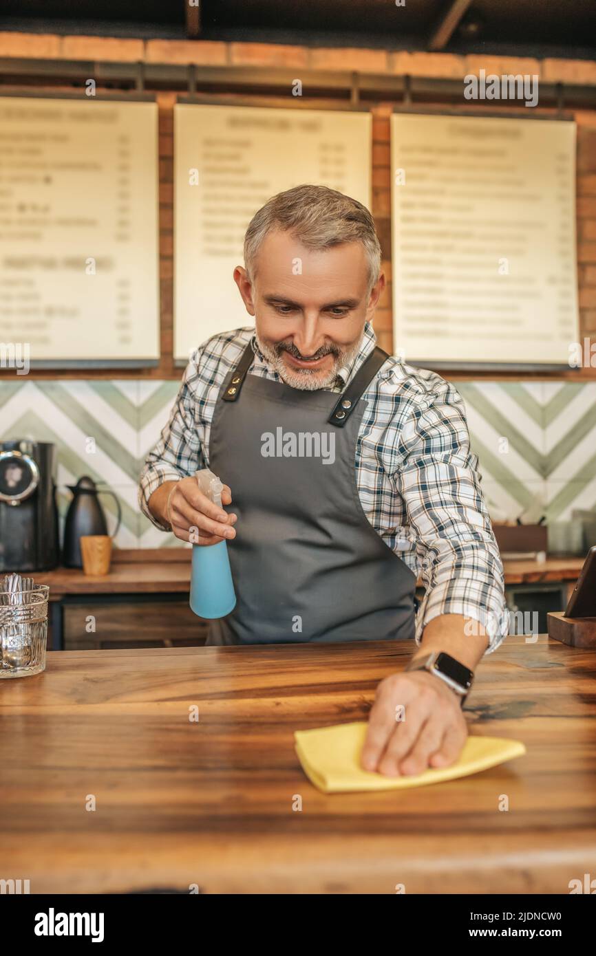 Man splashing detergent and wiping bar counter Stock Photo - Alamy