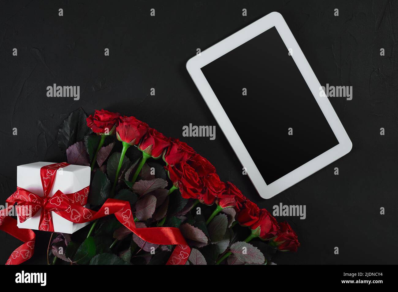 Top view fresh red rose flower and gift box on black deck with empty ...