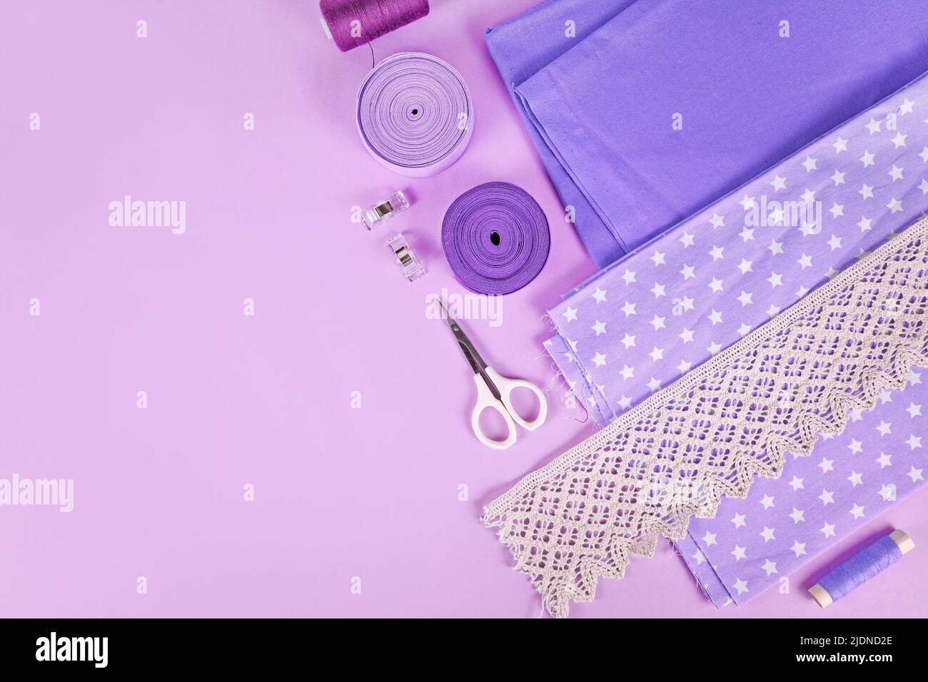 Sewing flat lay with various tools like fabric, scissors, spools and ...