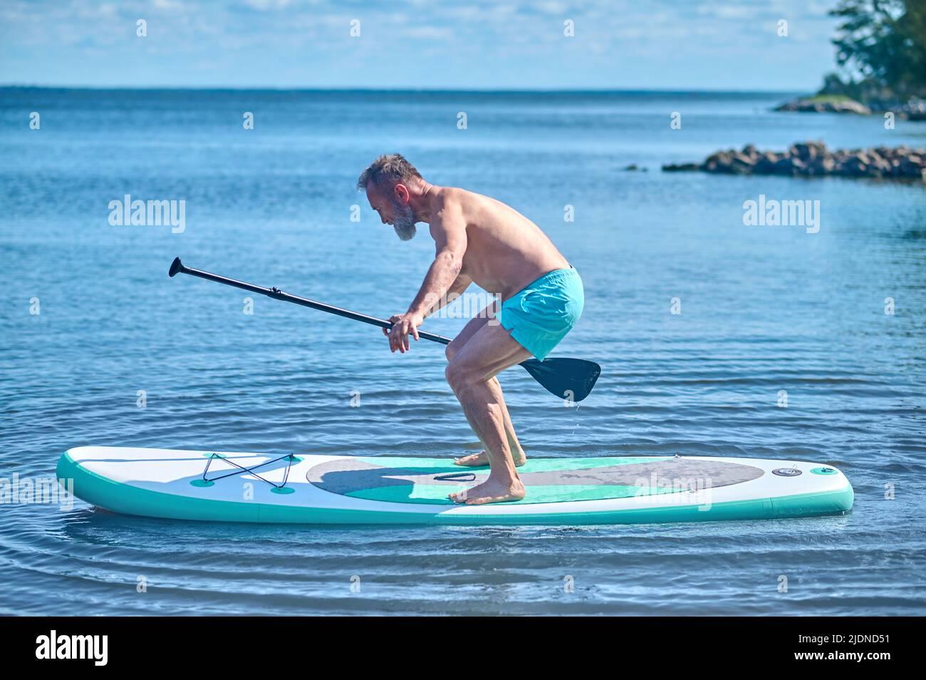 Man sideways to camera balancing on rowing board Stock Photo - Alamy