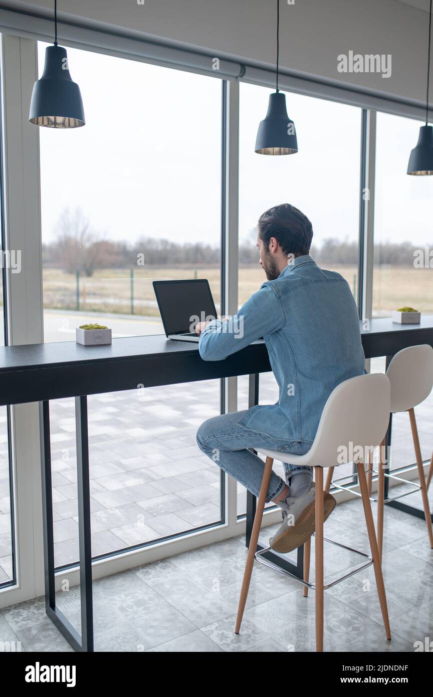 Back view of man sitting working on laptop Stock Photo - Alamy