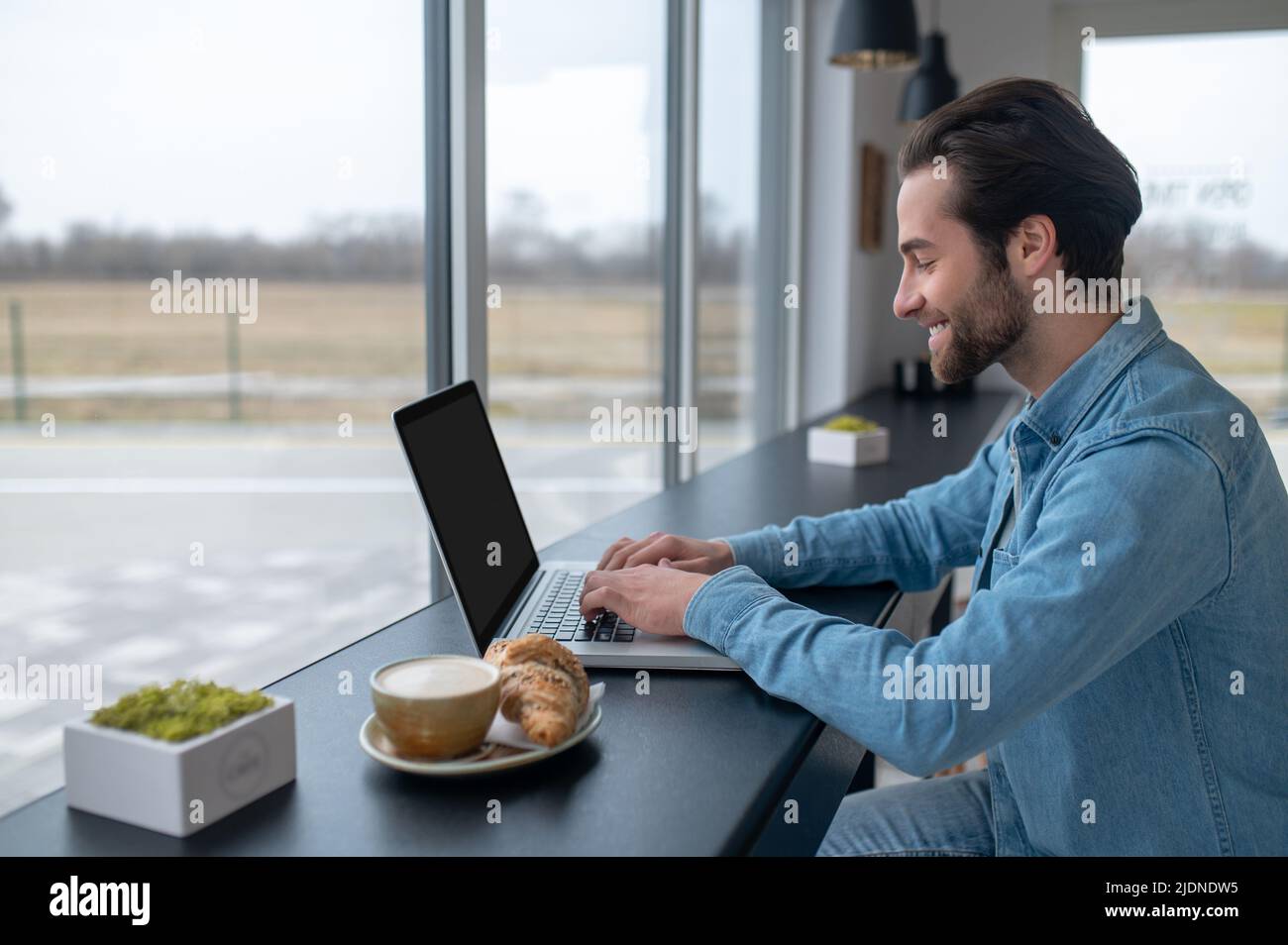 Man working on laptop sitting sideways to camera Stock Photo - Alamy
