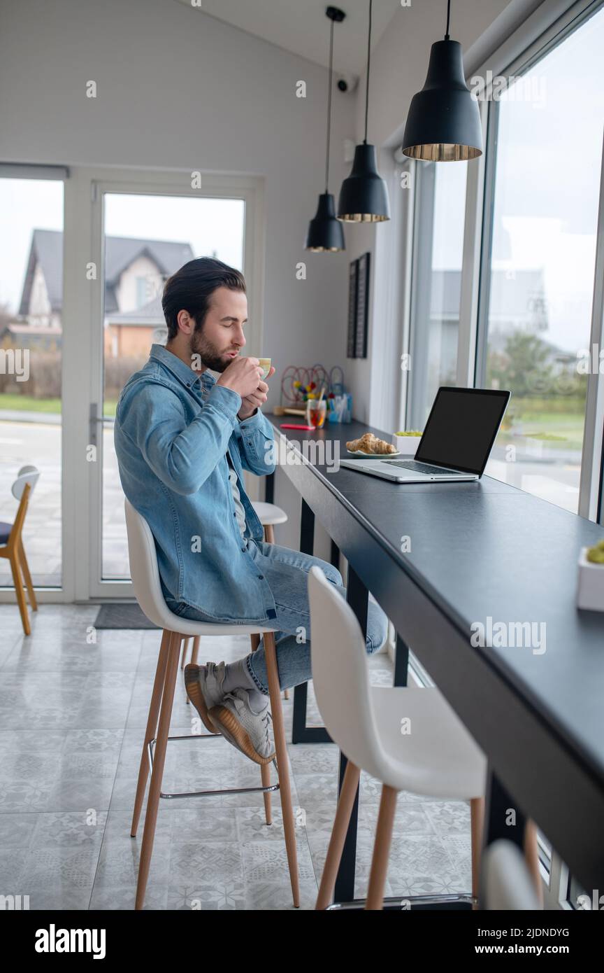 Man drinking coffee sitting sideways to camera Stock Photo - Alamy