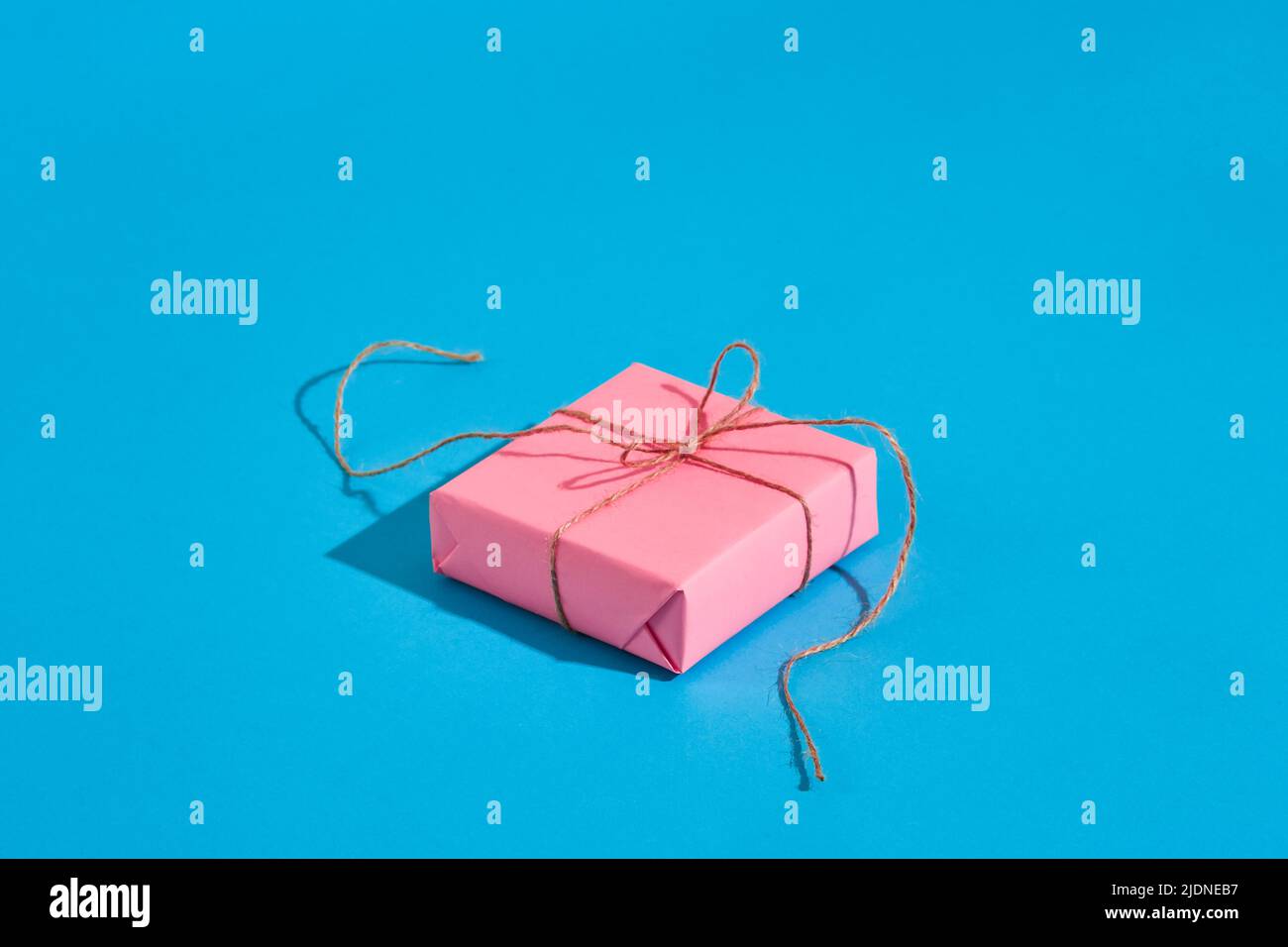 Pink gift box with thin tied rope with shadow on blue background Stock ...