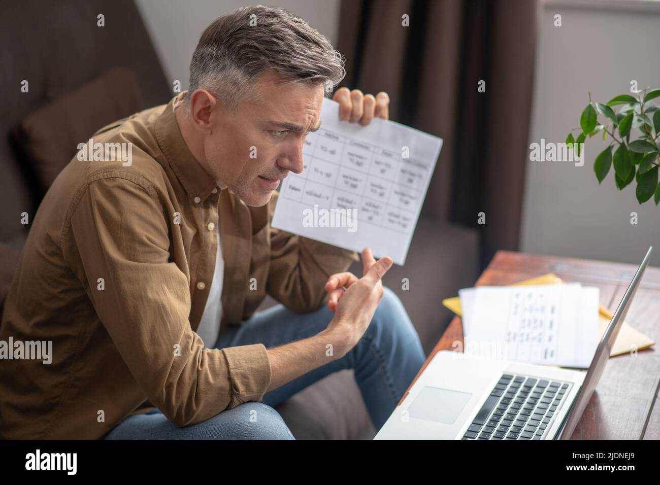 Man sitting showing document on laptop screen Stock Photo - Alamy
