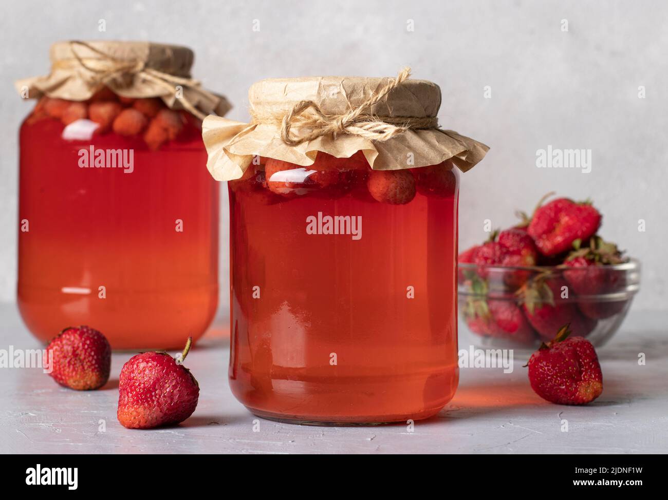 Homemade canned compote with strawberries in two jars on light gray ...