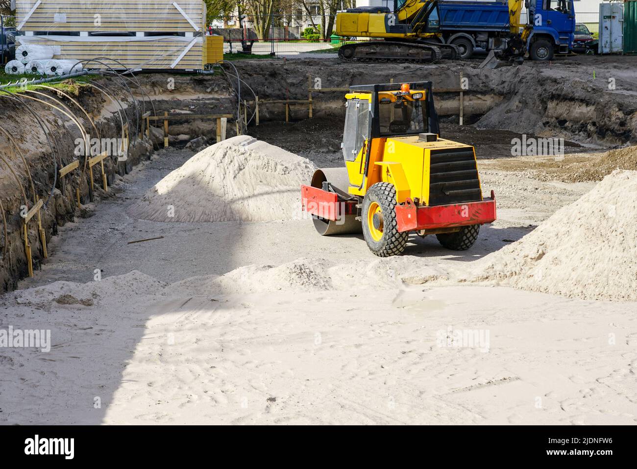 Construction pit of a new building with a heavy compaction roller, sand ...