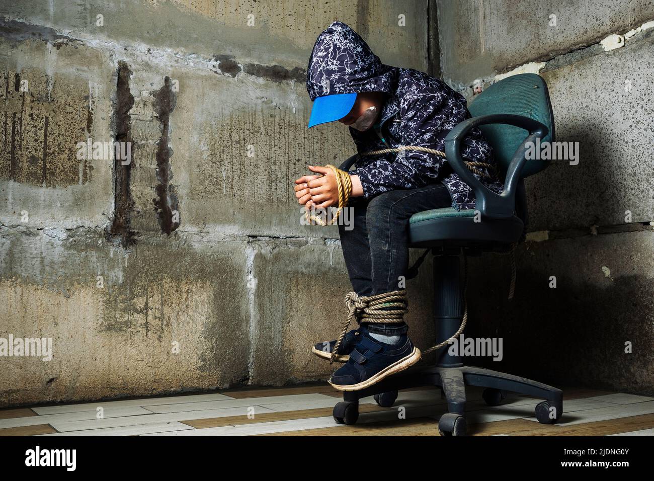 a child in the basement is sitting on a chair tied with a rope Stock ...