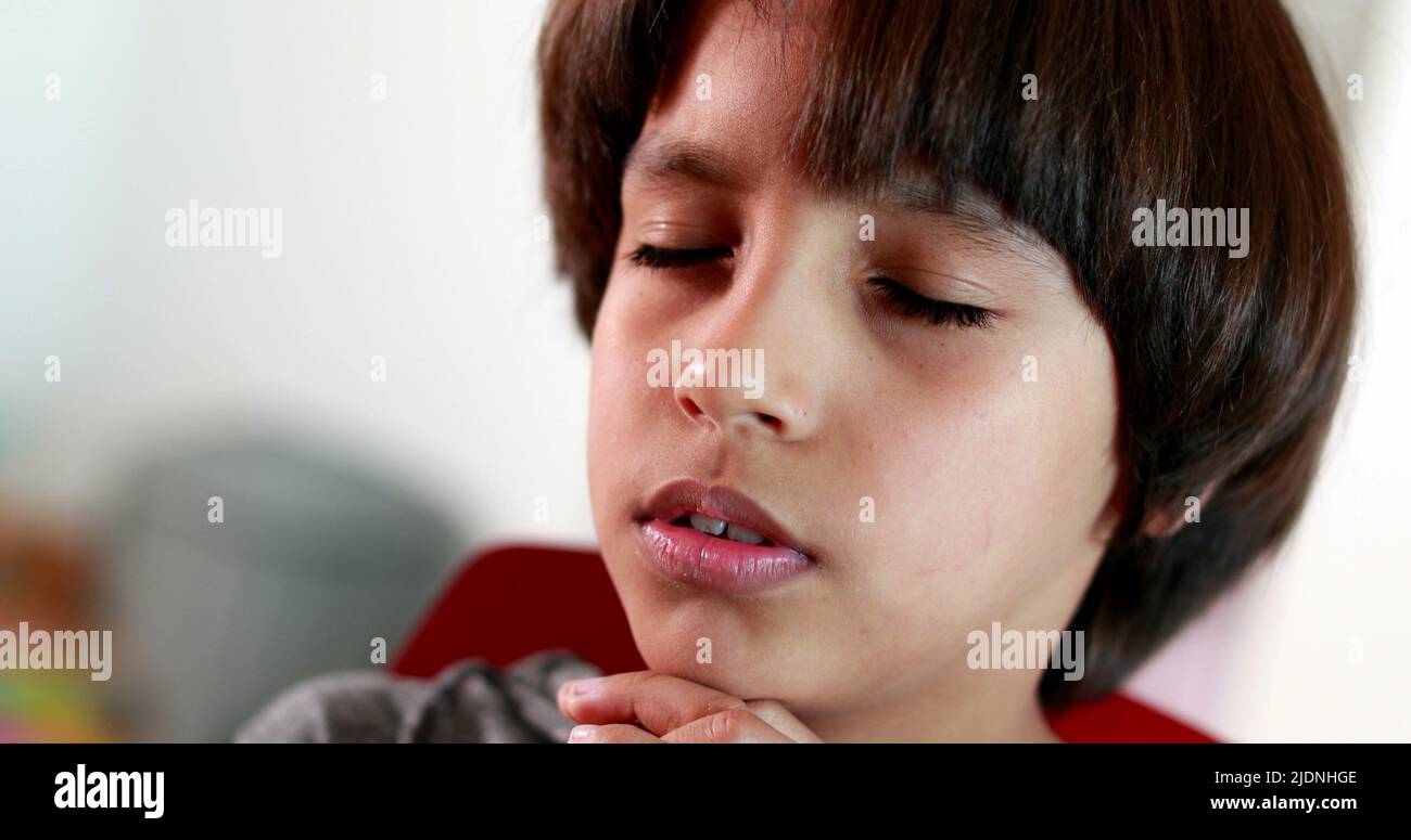Boy praying to God with hands held together. Mixed race child prays ...