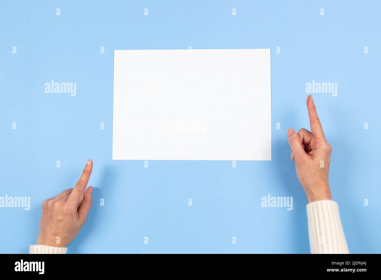 Female hands pointing to blank white paper sheet on light blue ...