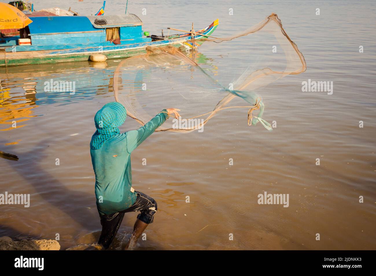 Fisherman using net to catch fishes Stock Photo - Alamy