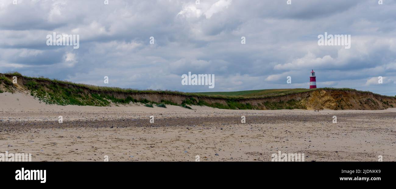 A panorama landscape of Happisburgh beach and lighthouse with tall sand ...