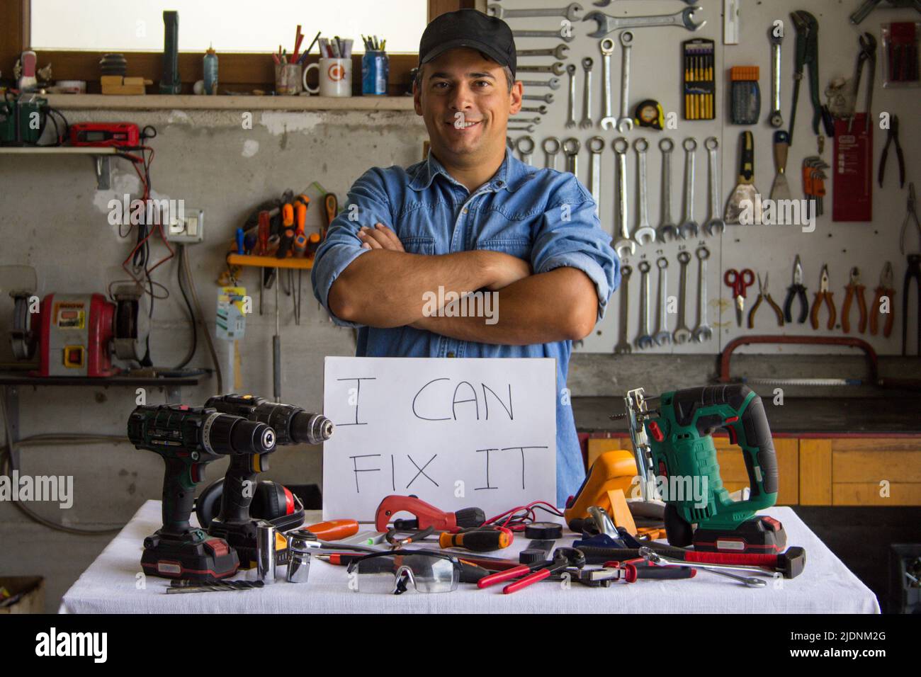 Handyman man with folded arms in his workshop with work tools in front ...