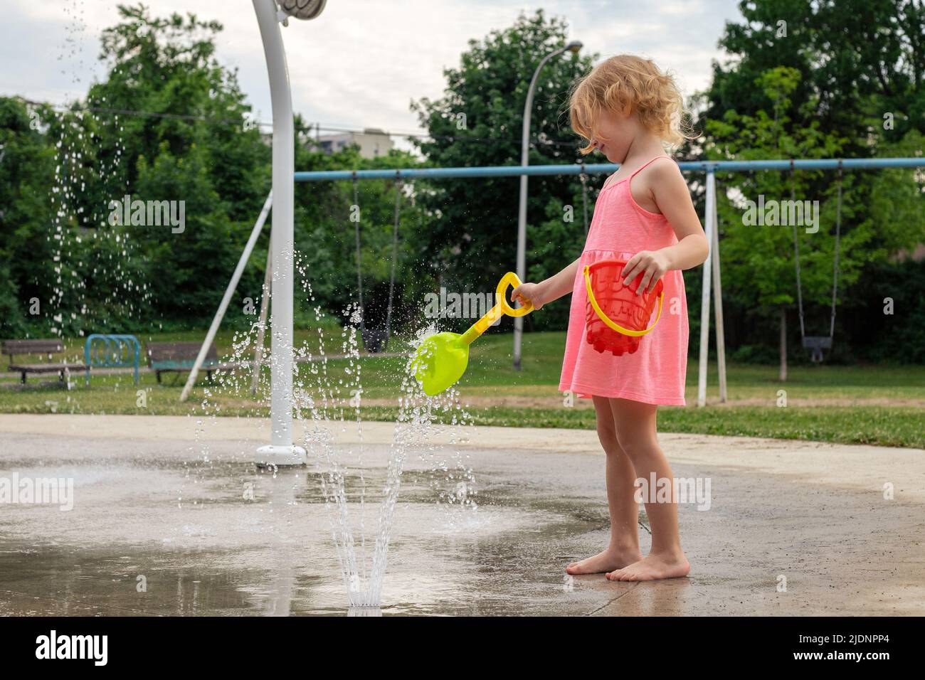 Little child playing with water and toys at splash pad in the local ...