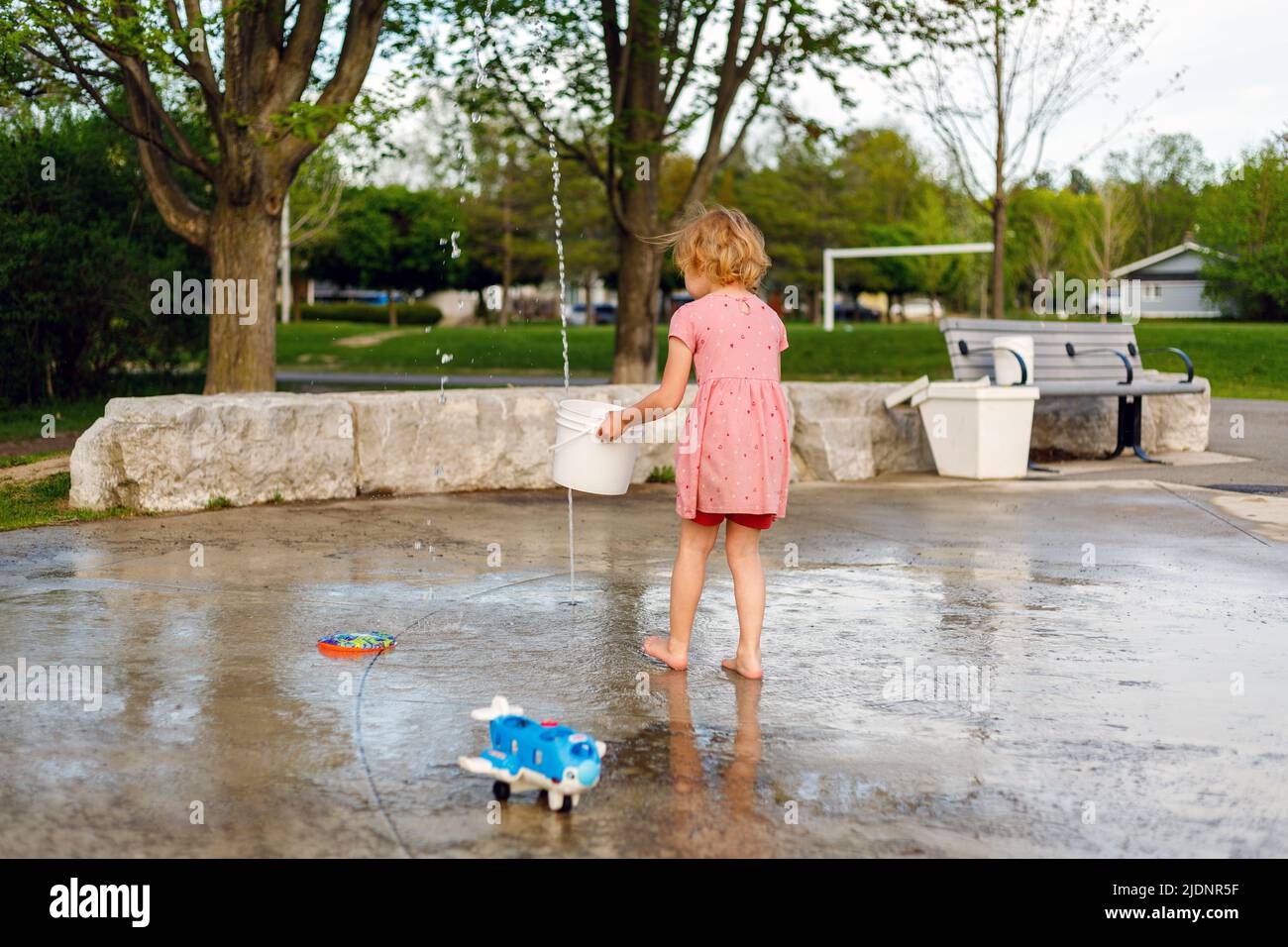 Splash pad for children in park in summer. Child playing with water and ...