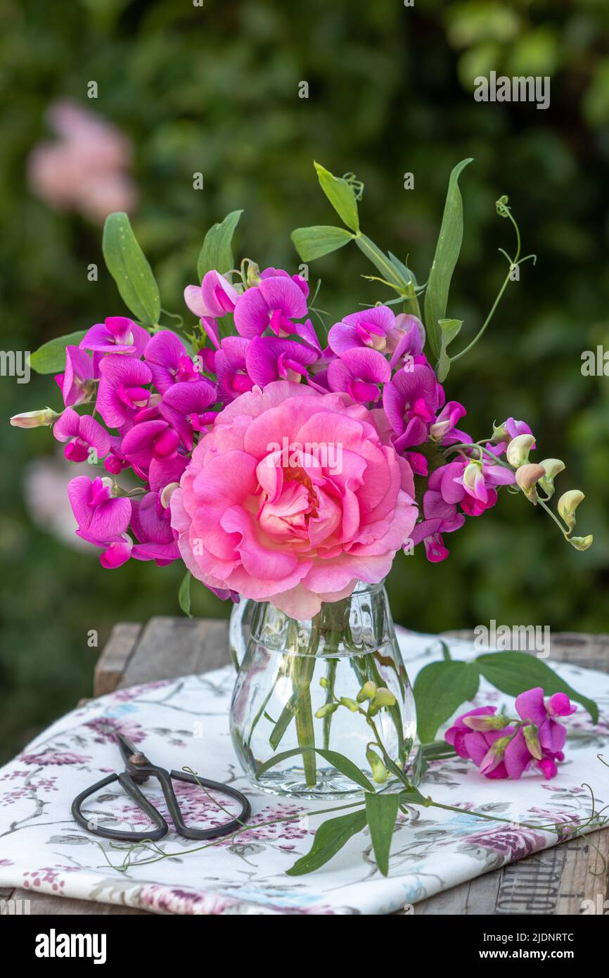 romantic bouquet of rink rose and vetches in glass vase Stock Photo - Alamy