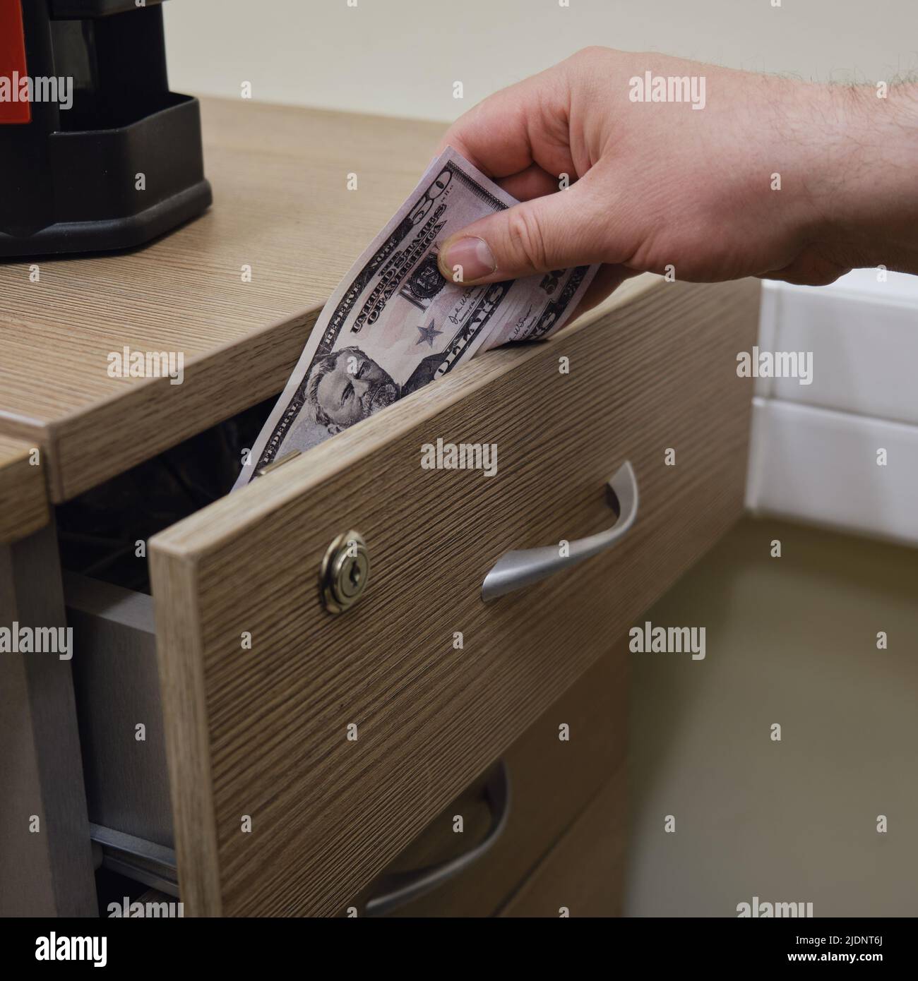 Man hand takes money out of an office desk drawer Stock Photo - Alamy