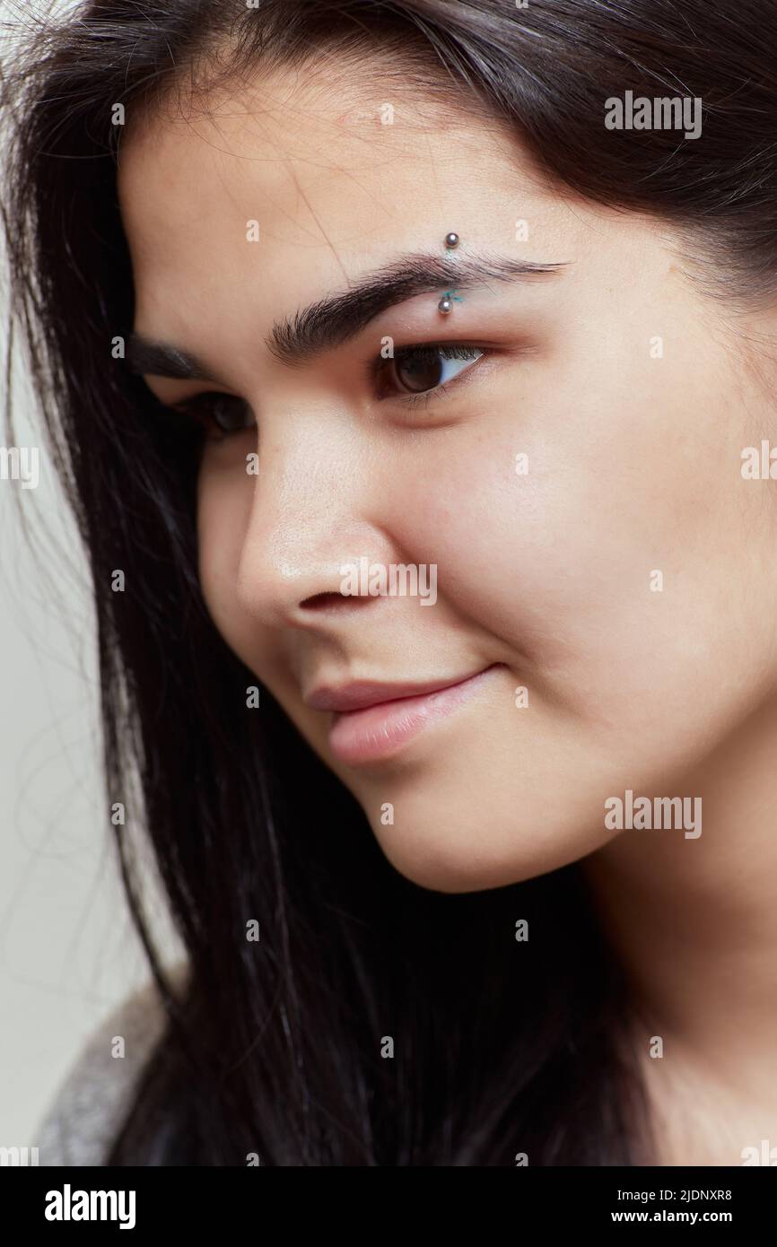 Professional placing the jewel of piercing on the temple on the head ...