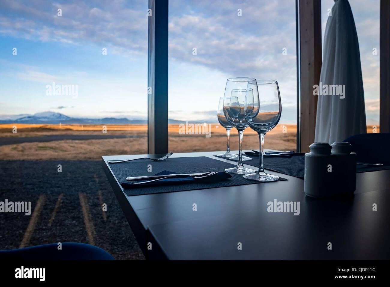 Wineglasses on table against window with view of sky at restaurant in ...