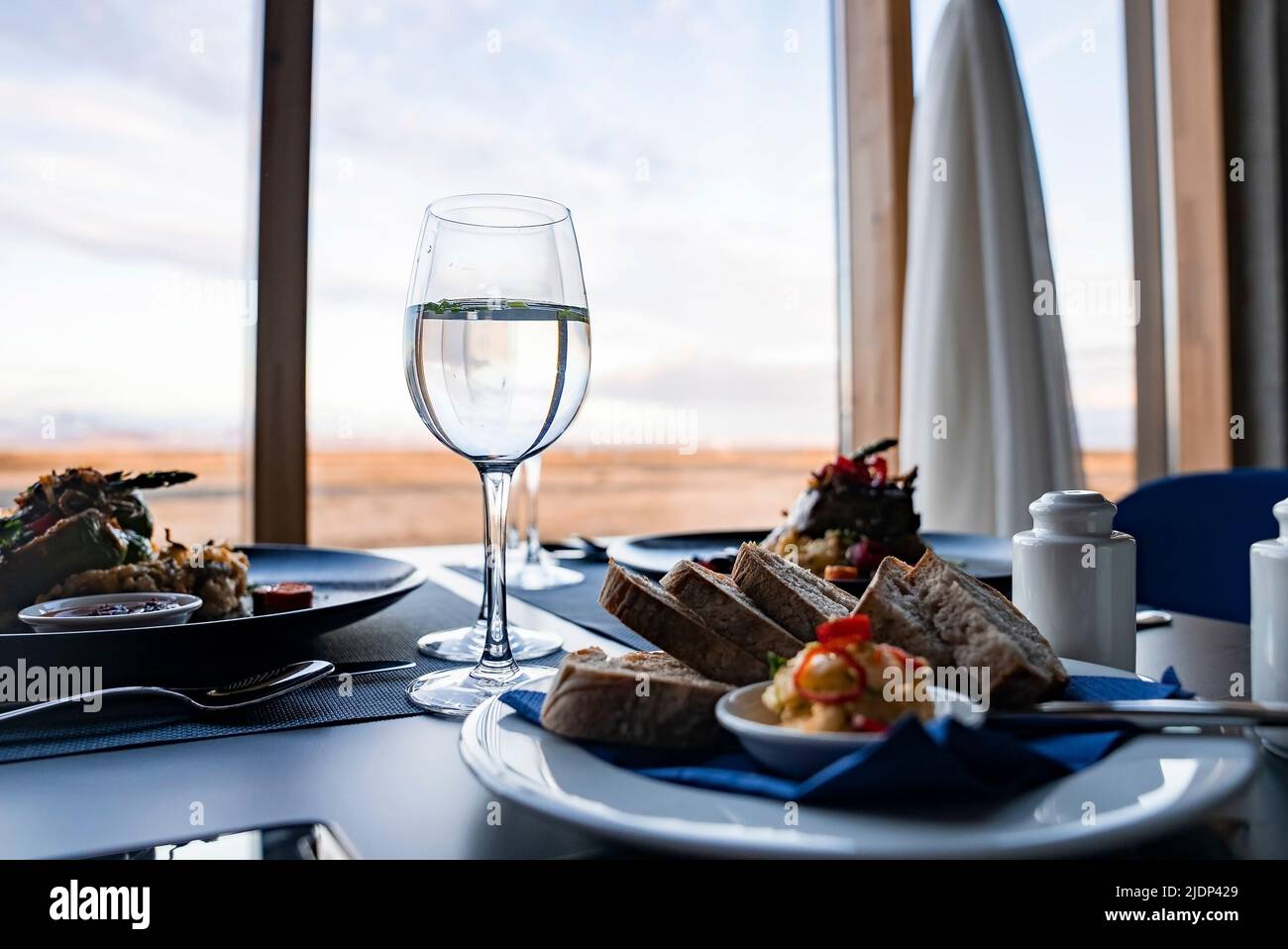Tasty food and wineglasses on dining table against window at restaurant ...