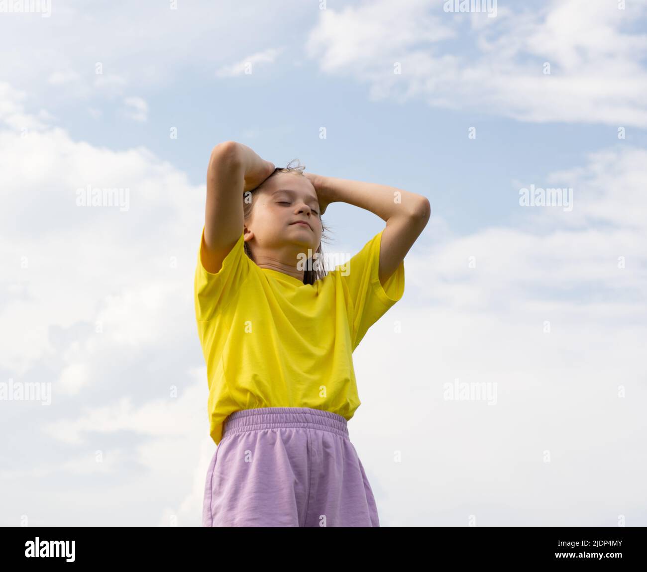 Girls blonde wearing yellow T-shirt on blue sky background ...