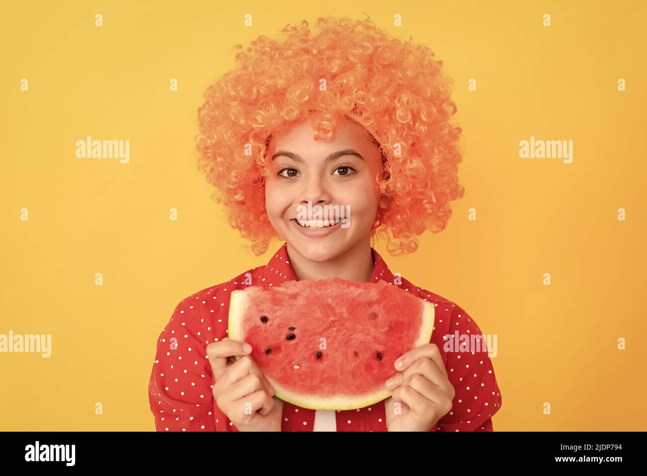 cheerful kid in fancy orange hair wig holding fresh ripe water melon ...