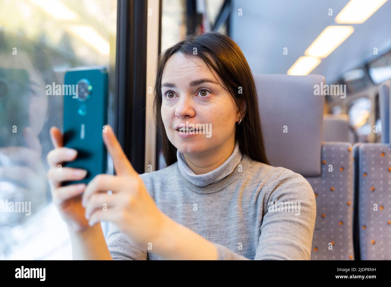 Interested female traveler filming landscapes behind glass in express ...