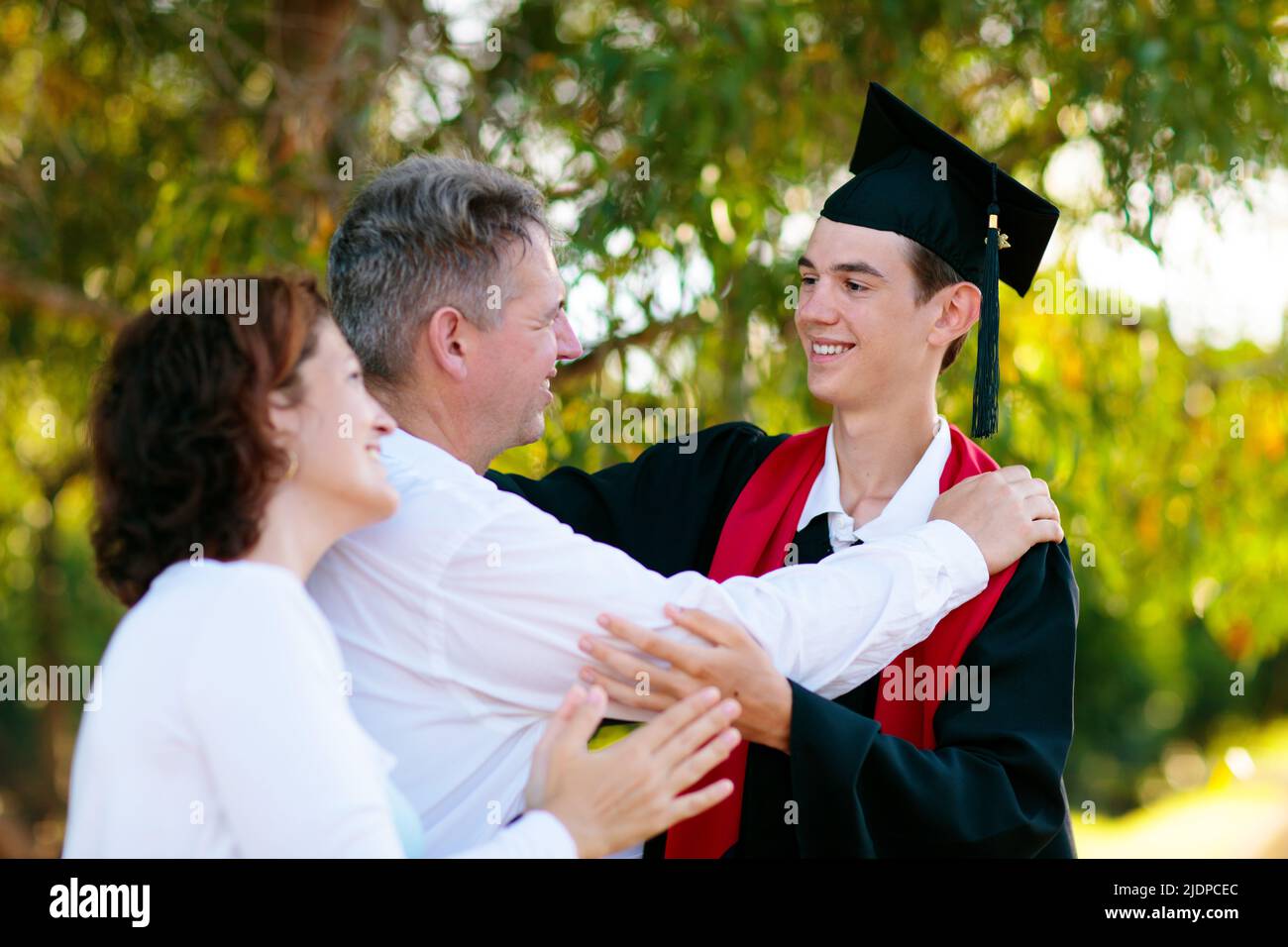 School or college graduation ceremony. Young man in gown and cap, with ...