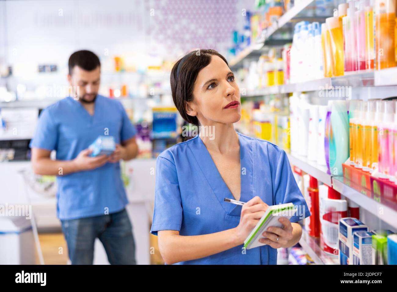 Diligent female pharmacist noting assortment of drugs in pharmacy Stock ...