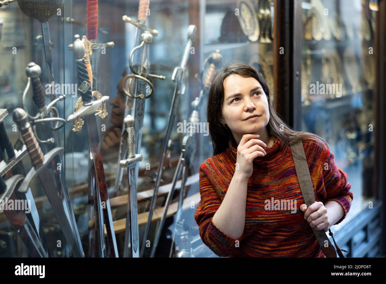 Female traveler viewing at handmade forged swords in gift shop of ...