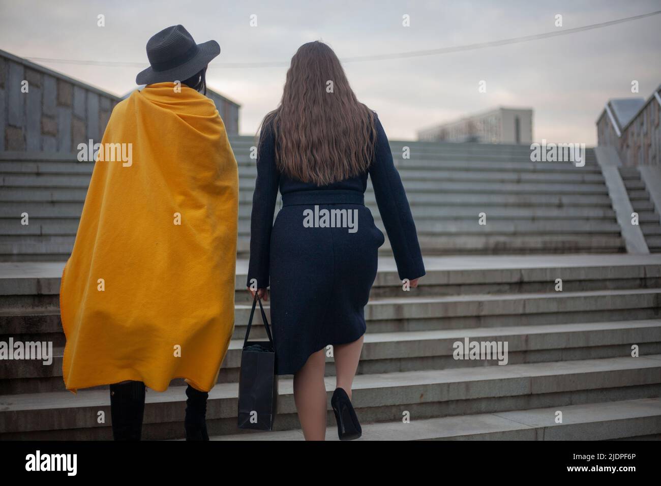 Girls climb stairs. Women walk through city. Walk through town square ...