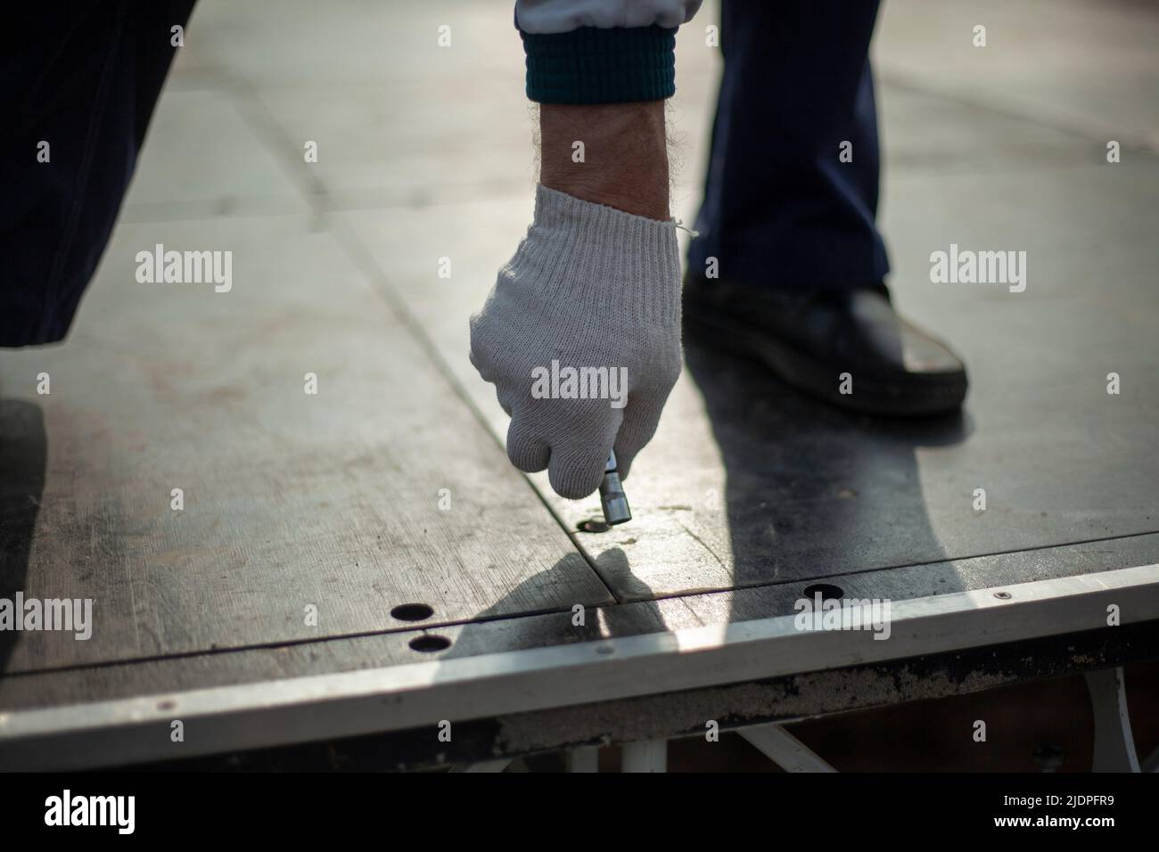 Worker holds bolt. Man tightens screw. Guy assembles structure. Fitting ...