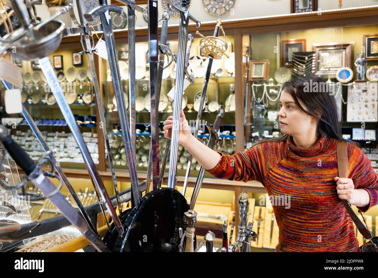 Woman choosing old-fashioned sword in souvenir shop Stock Photo - Alamy