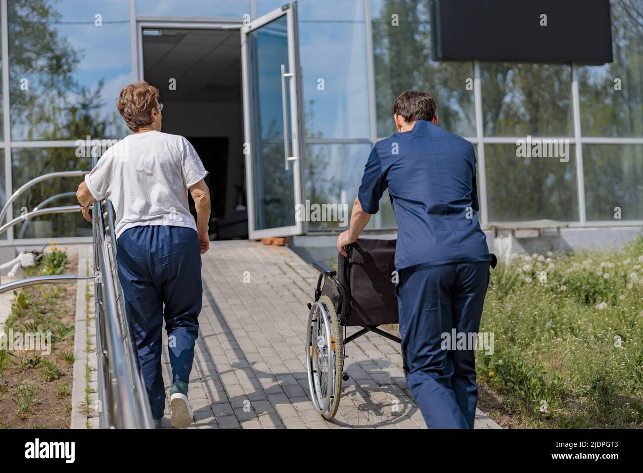 Patient and nurse turn around at clinic after a walk in courtyard Stock ...