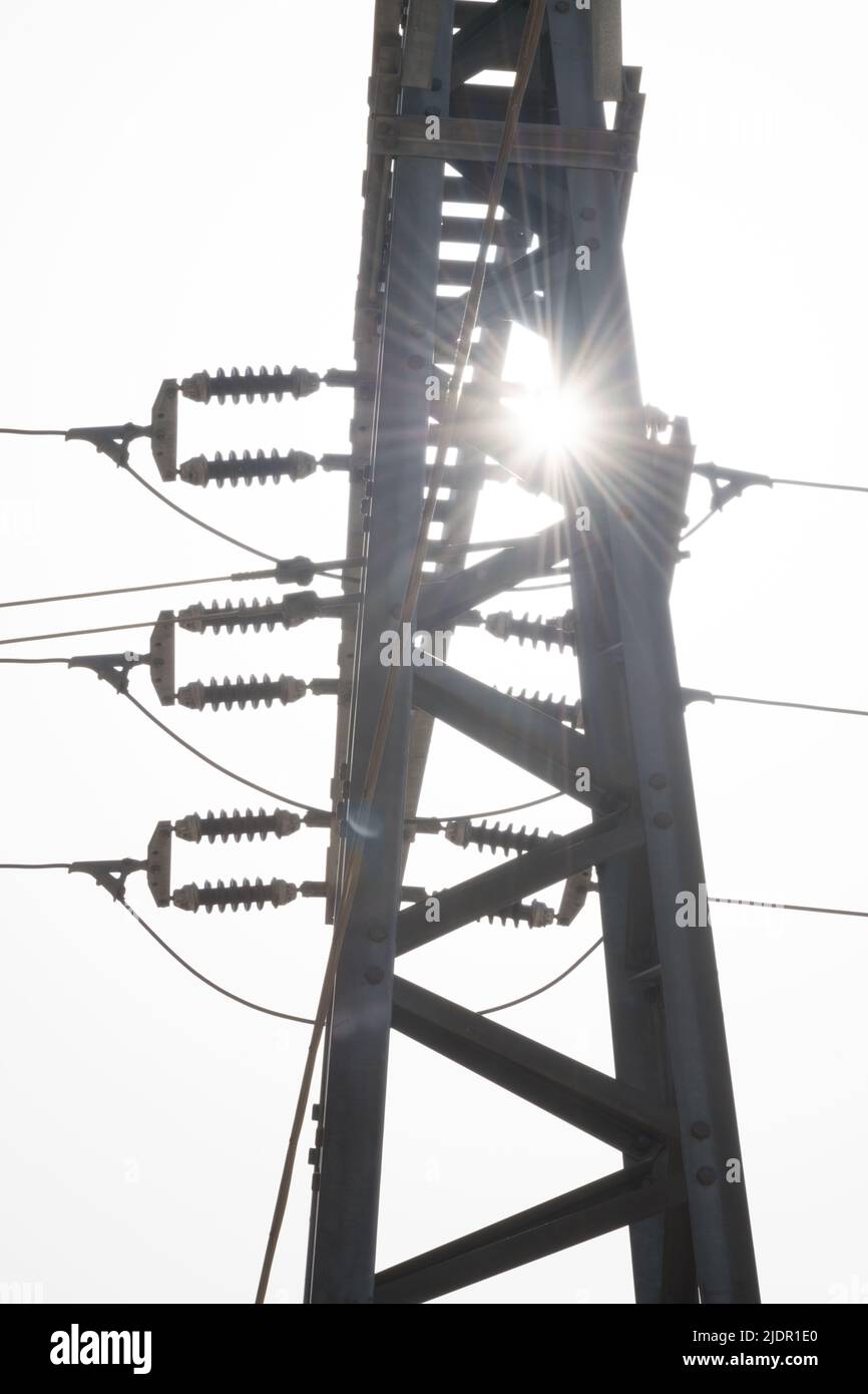 dark silhouette of massive iron steel power pole seen from below ...
