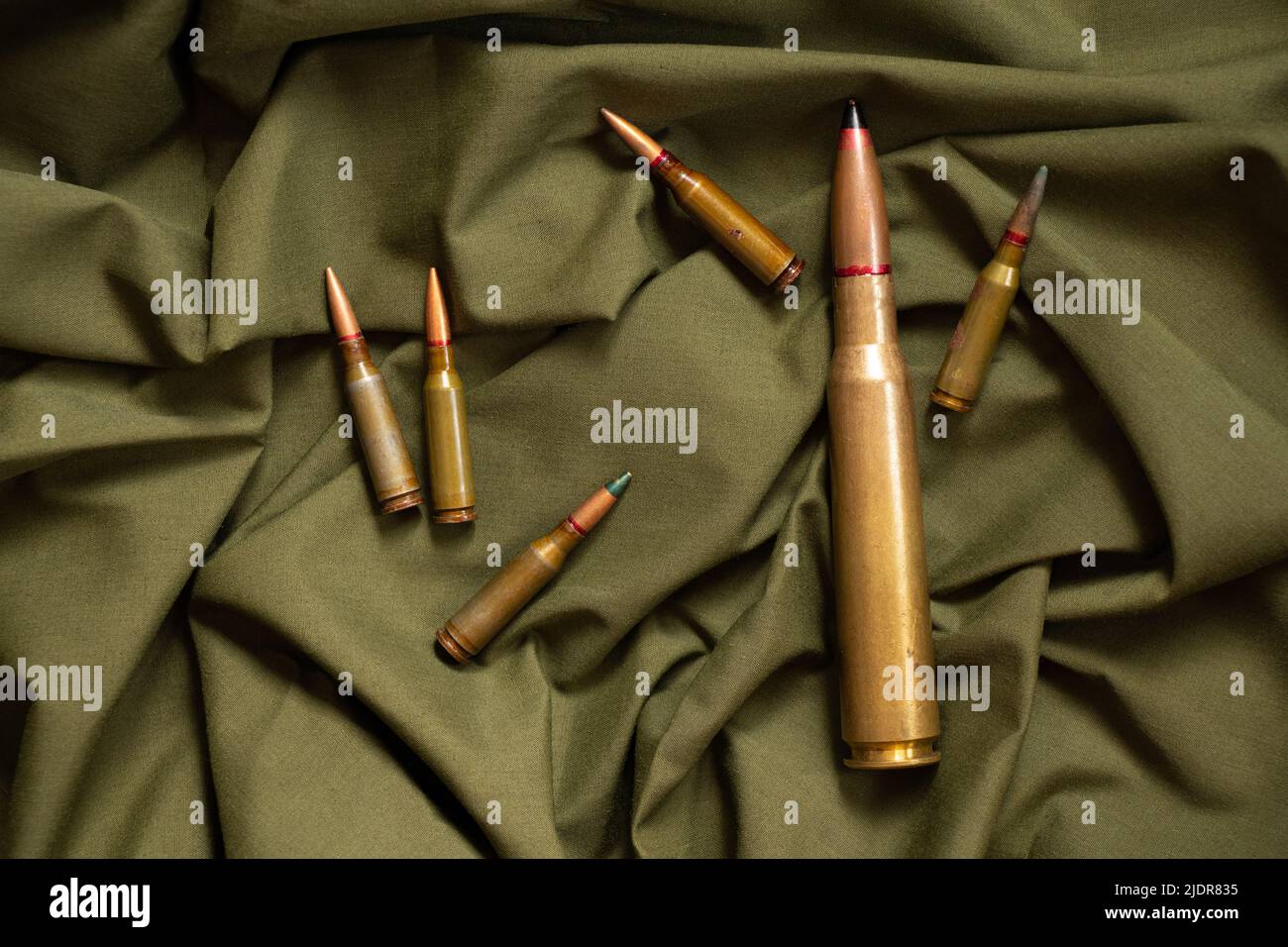 Bullets lie on a green camouflage background, military weapons ...