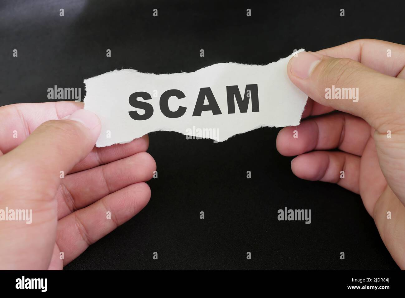 Scammed victim concept. Hand holding a piece of paper with word scam in ...