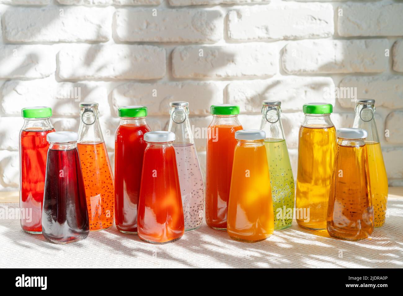Row of glass bottles of different juices against white brick wall Stock ...