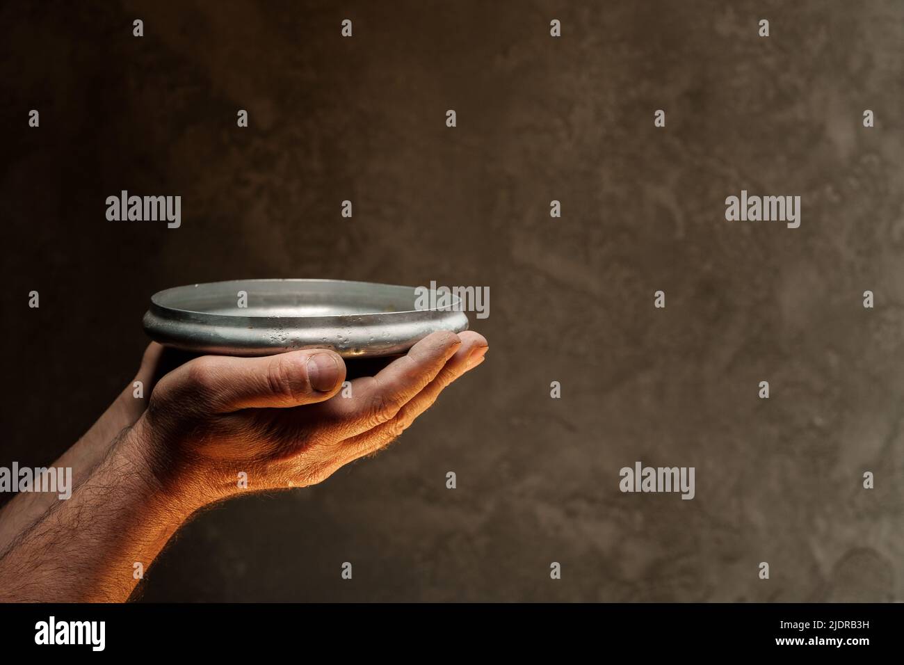 Male hands holding empty plate on dark background, lack of food, hunger ...