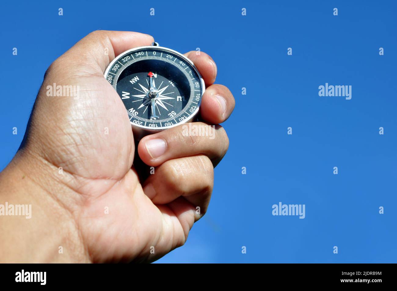 Hand holding the navigation compass blue sky background Stock Photo - Alamy