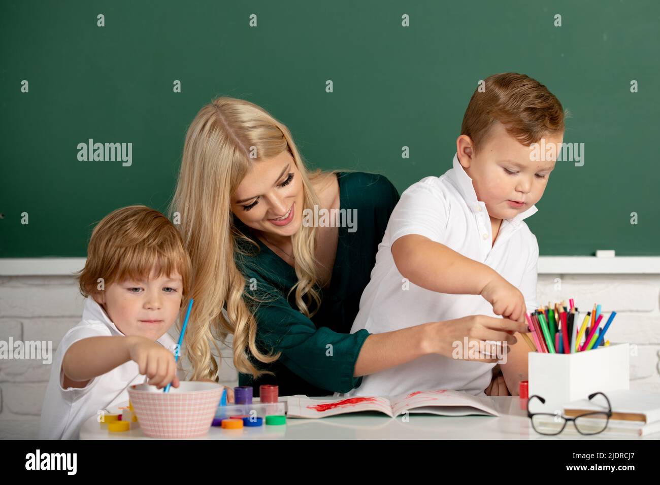 Little children with kindergarten teacher drawing at table indoors ...