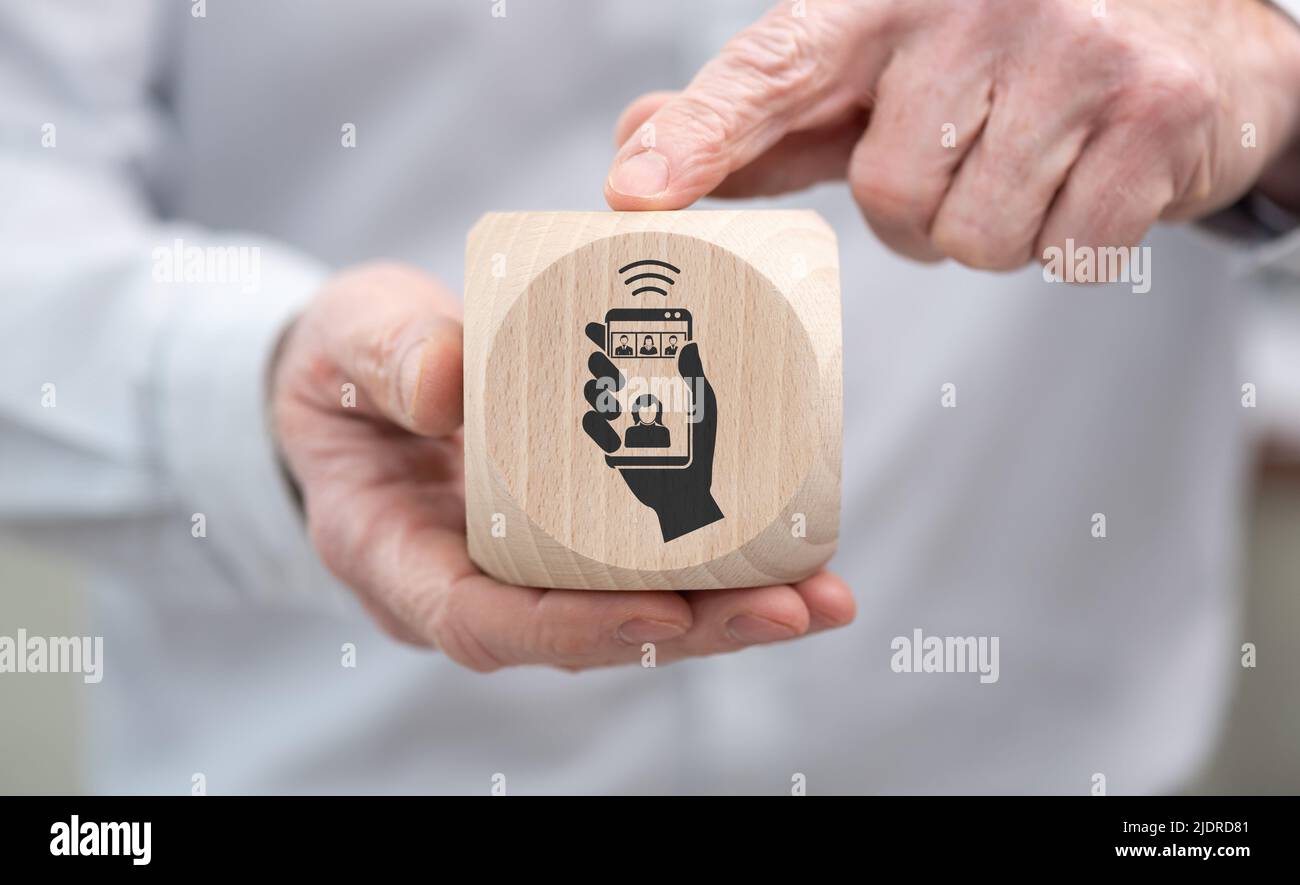 Hand holding a wooden cube with symbol of video conference concept ...
