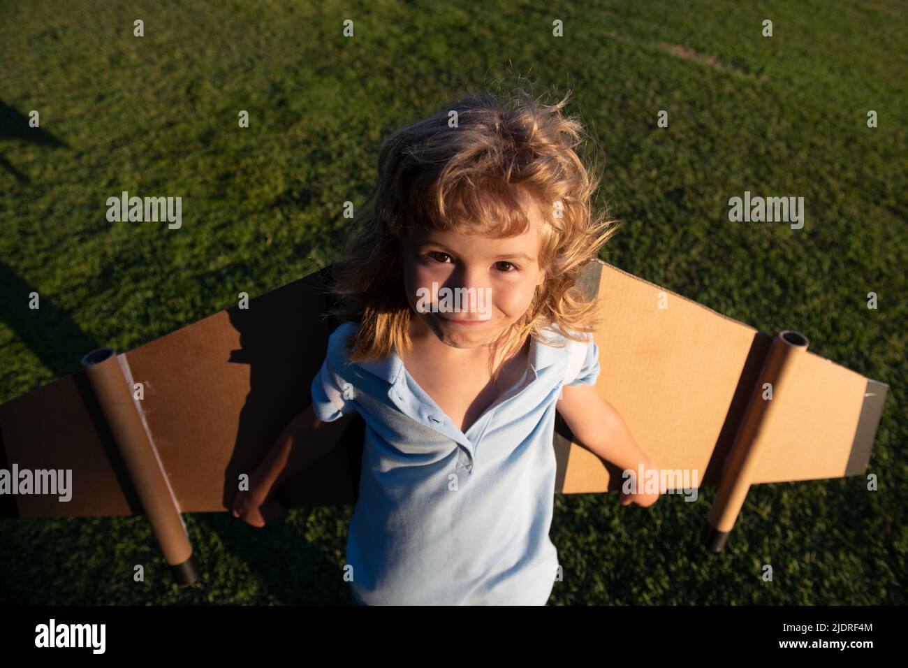 Funny child flying in plane made craft of cardboard wings. Dream ...