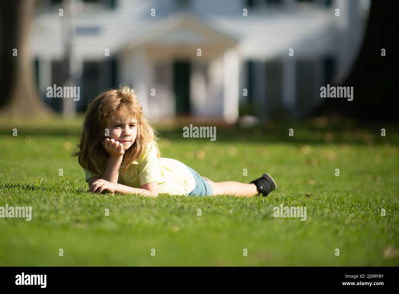 Happy child lying on green grass. Smiling boy having fun outdoor in ...