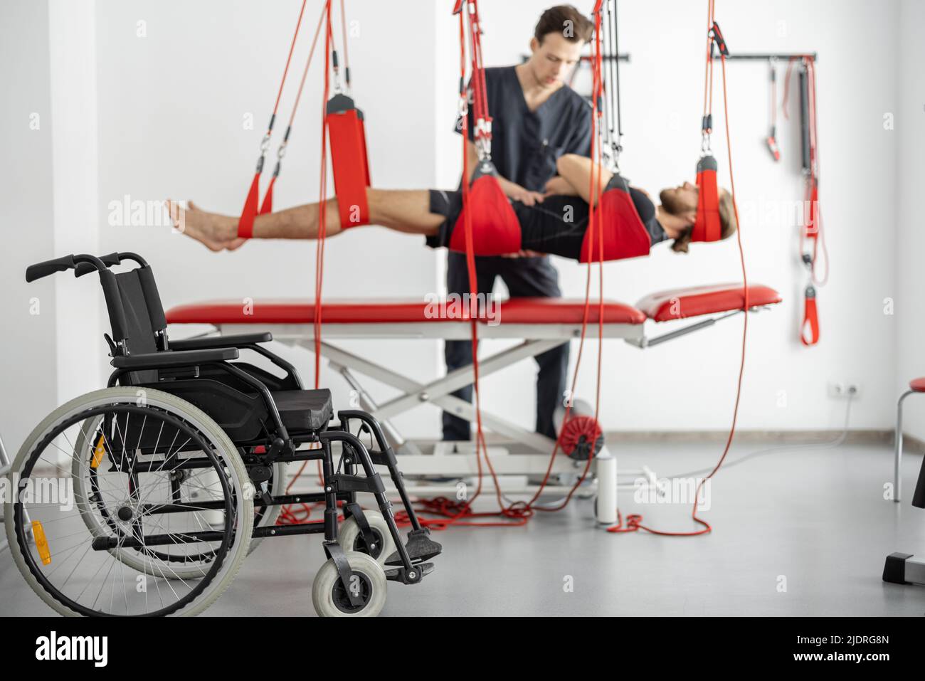 Rehabilitation specialist doing active treatment on suspension straps ...