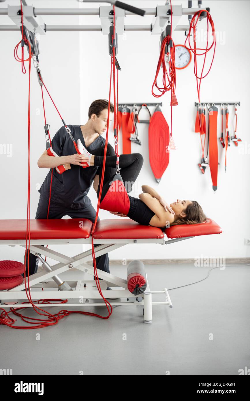 Rehabilitation specialist doing active treatment on suspension straps ...