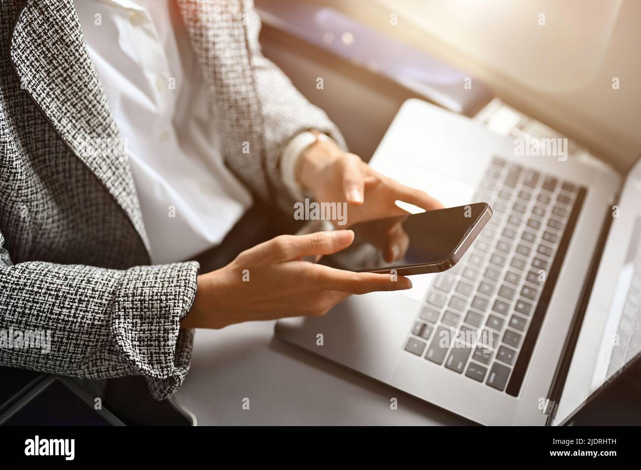 A businesswoman or female passenger at her seat using a smartphone and ...