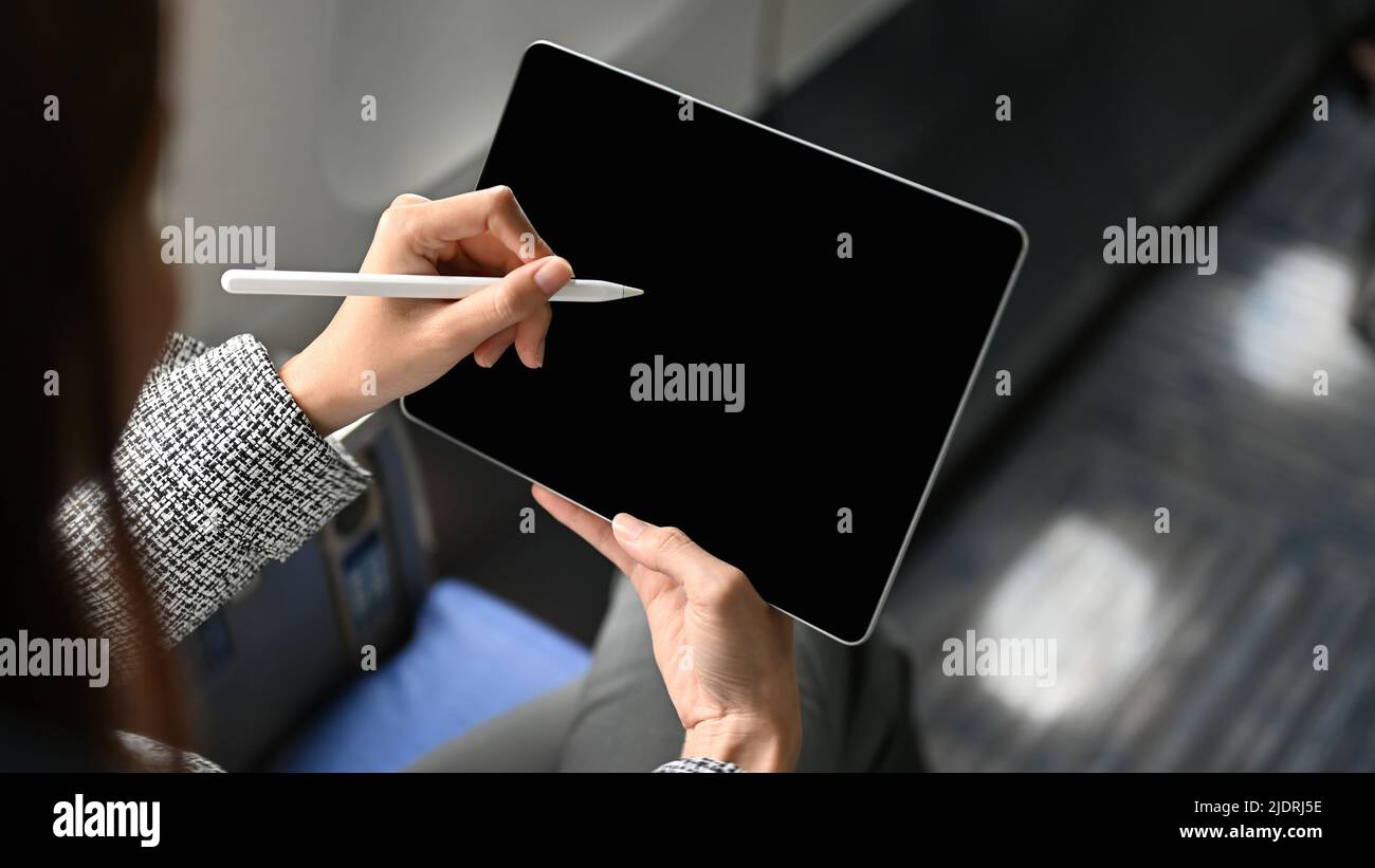 Overhead view of a female passenger using a portable digital tablet ...