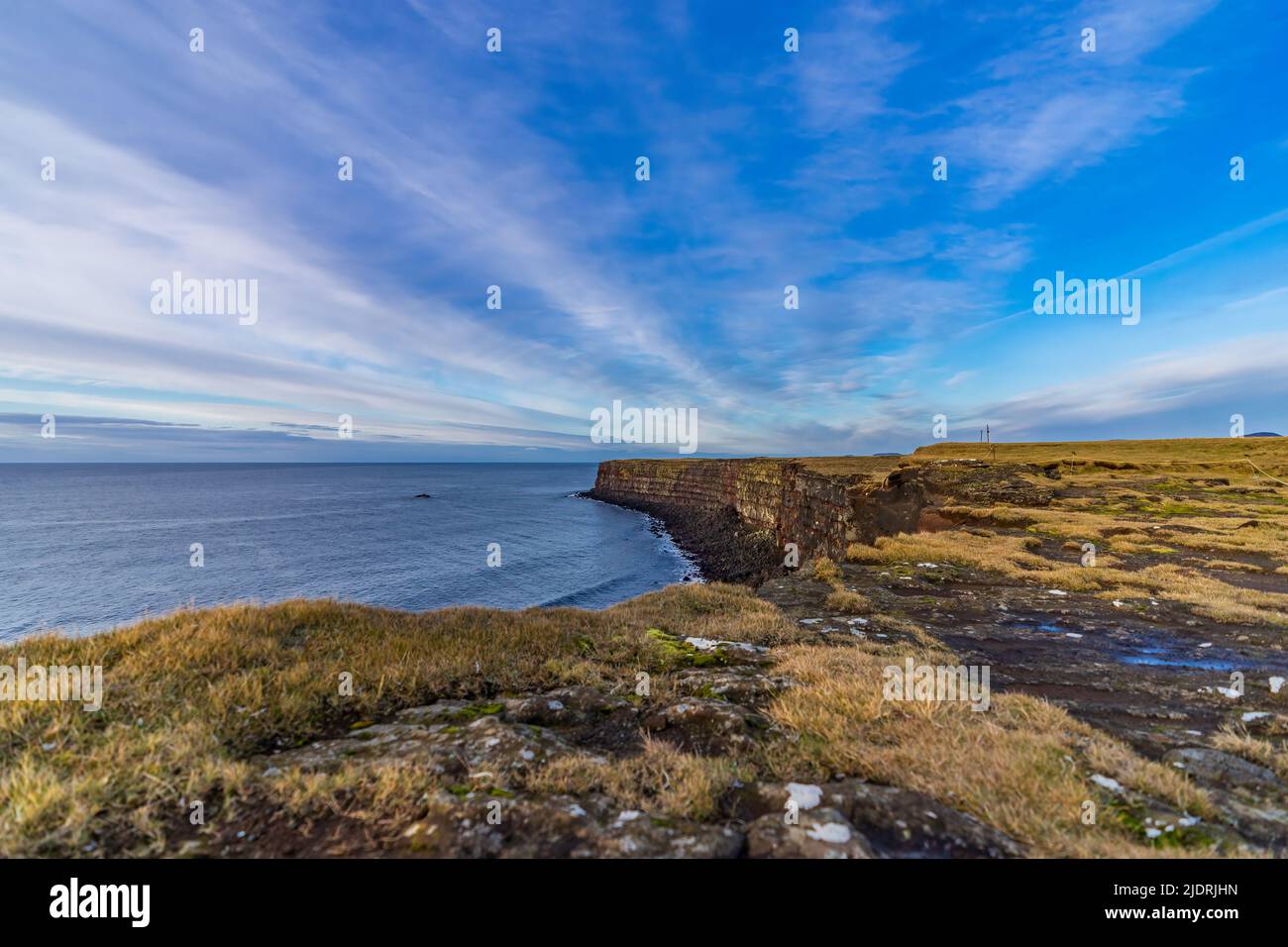 Spectacular steep cliffs with red seams in Iceland Stock Photo - Alamy